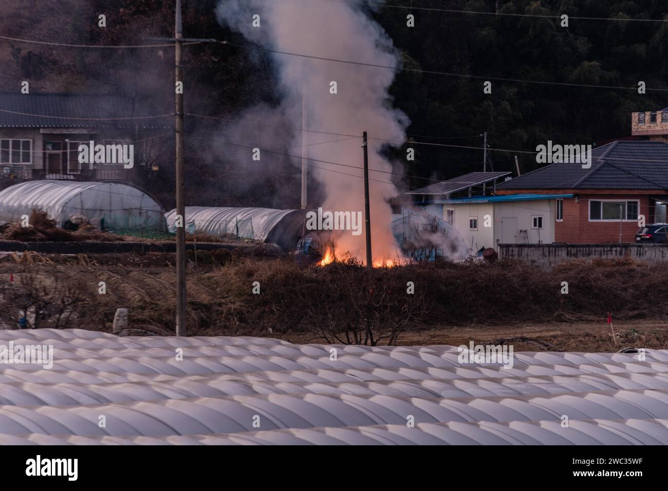 Large open fire with yellow flames and billowing smoke outside near a ...