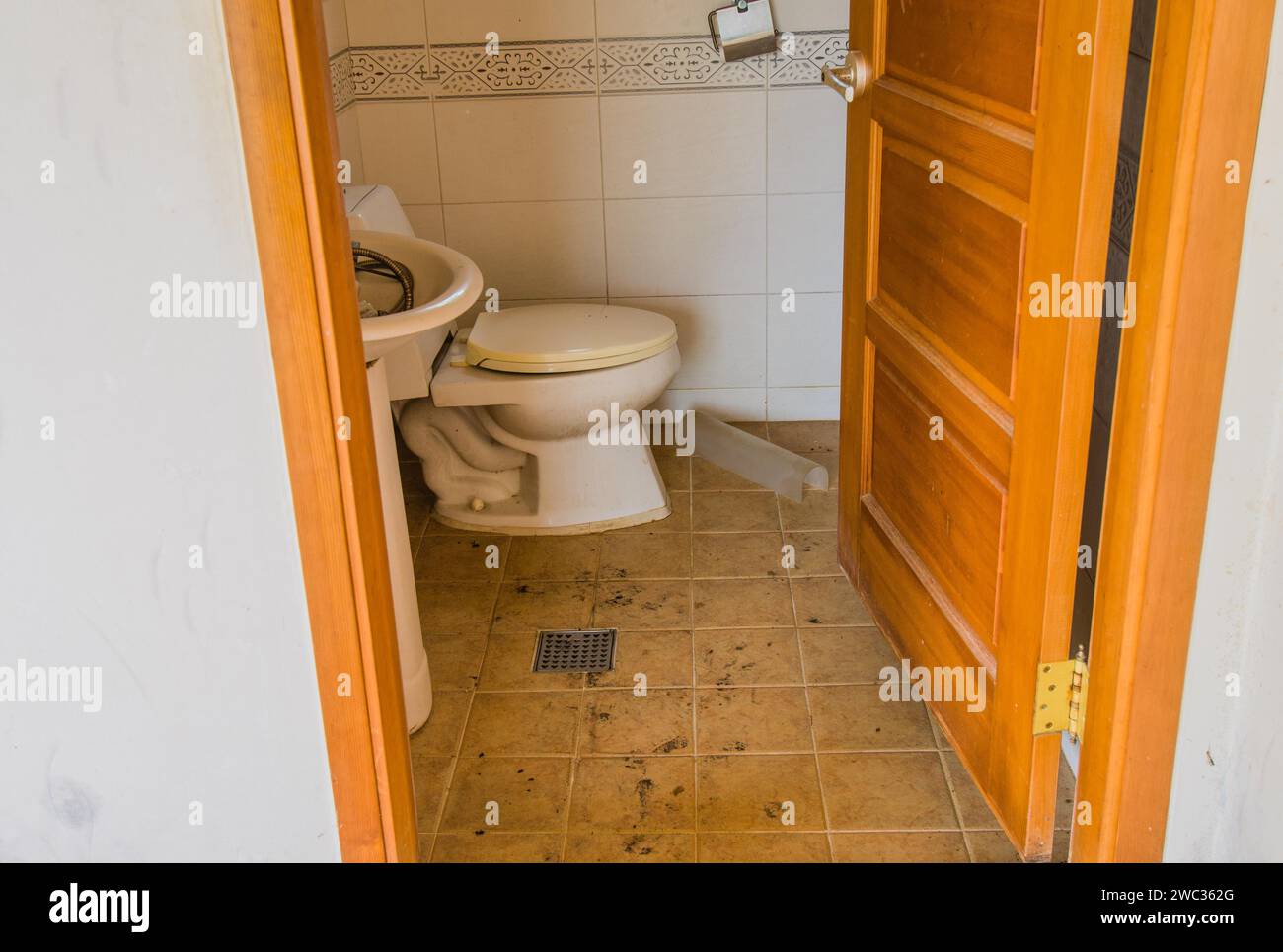 Grungy half-bath with sink full of debris and dirty commode in ...