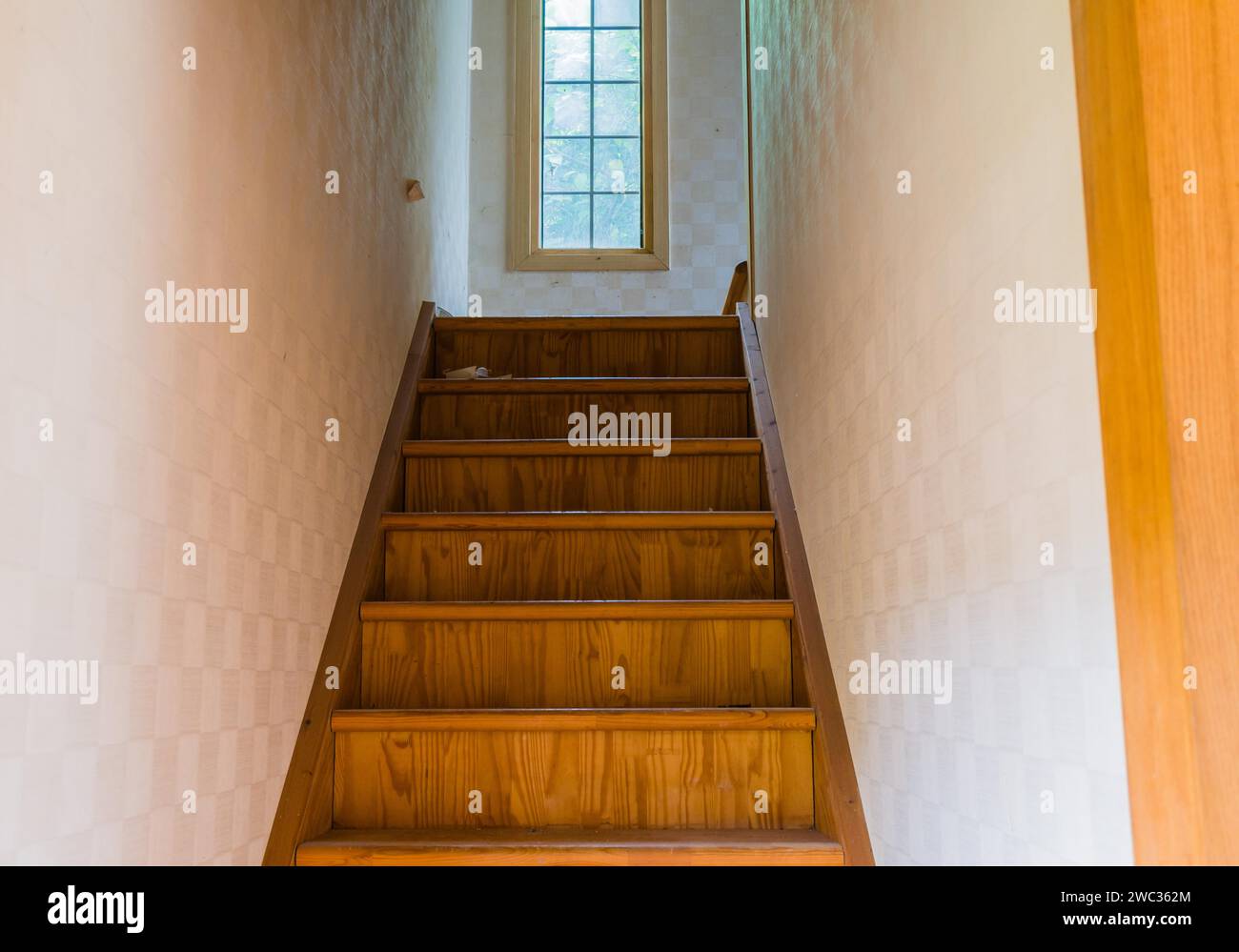 Wooden staircase with window on second floor landing in abandoned house ...