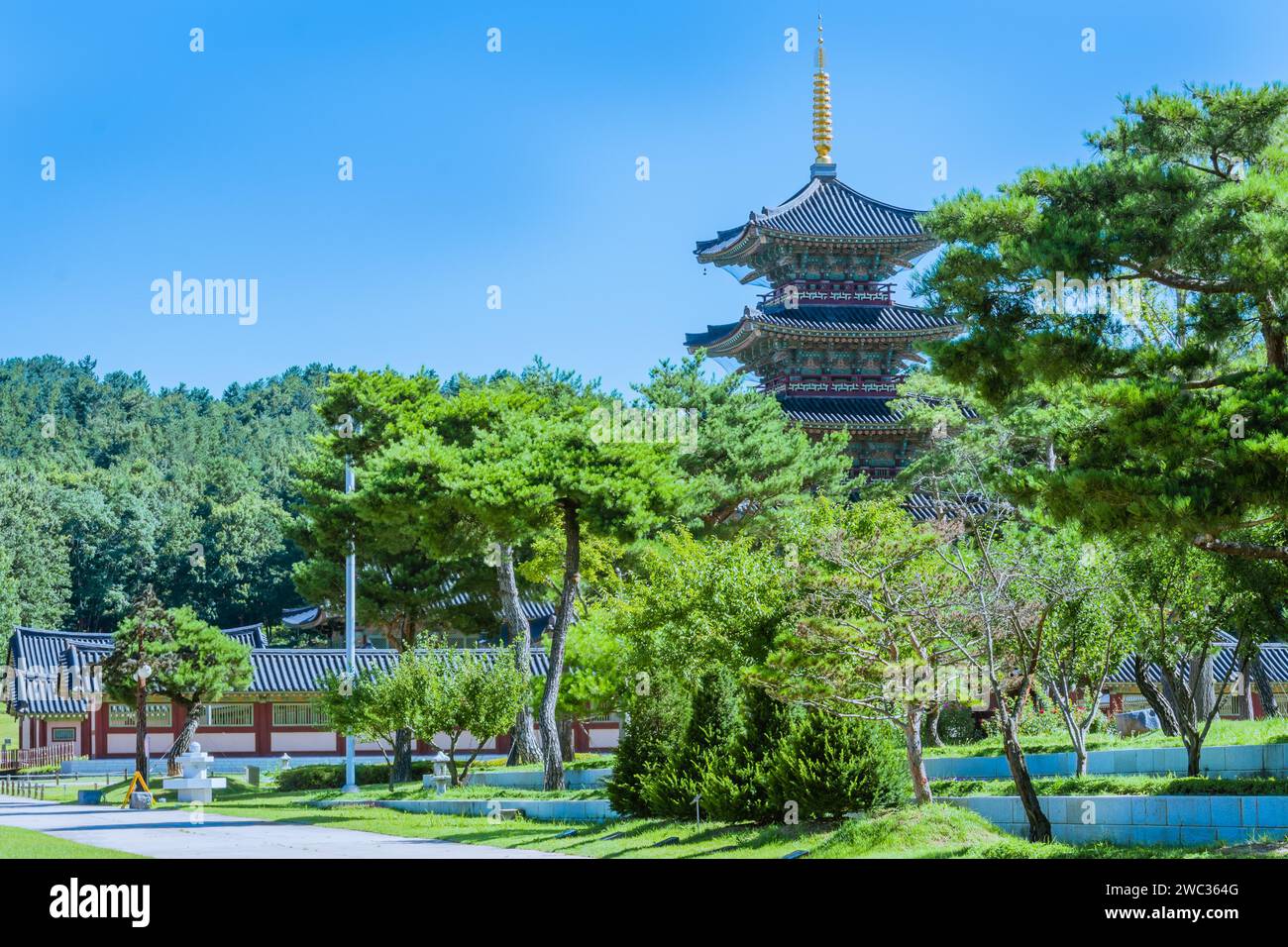 Tall oriental pagoda with tiled roof and golden spire and partial view ...