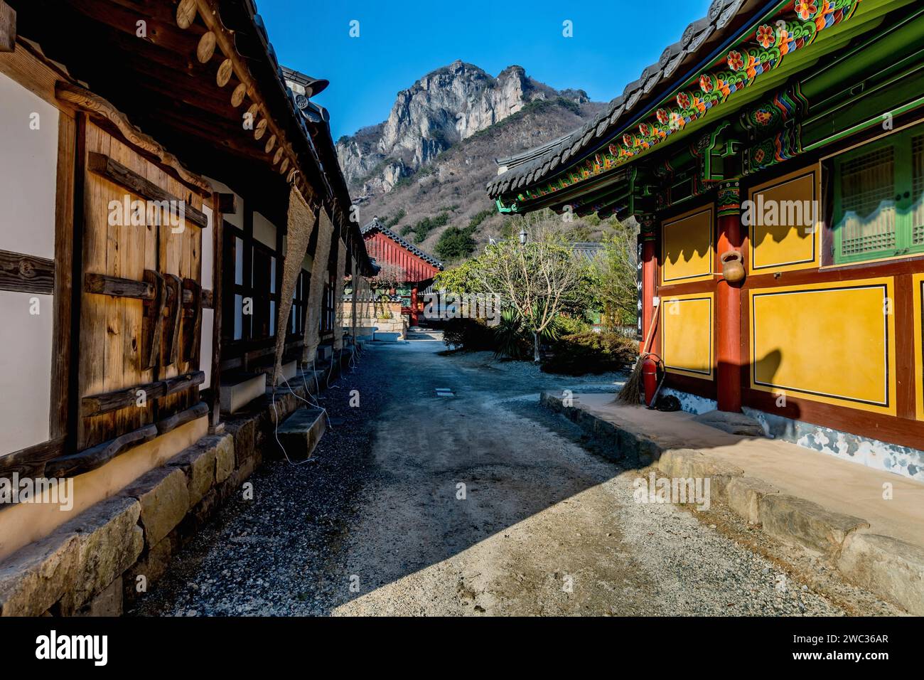 Walkway between buildings at Buddhist temple with mountain cliffs in ...