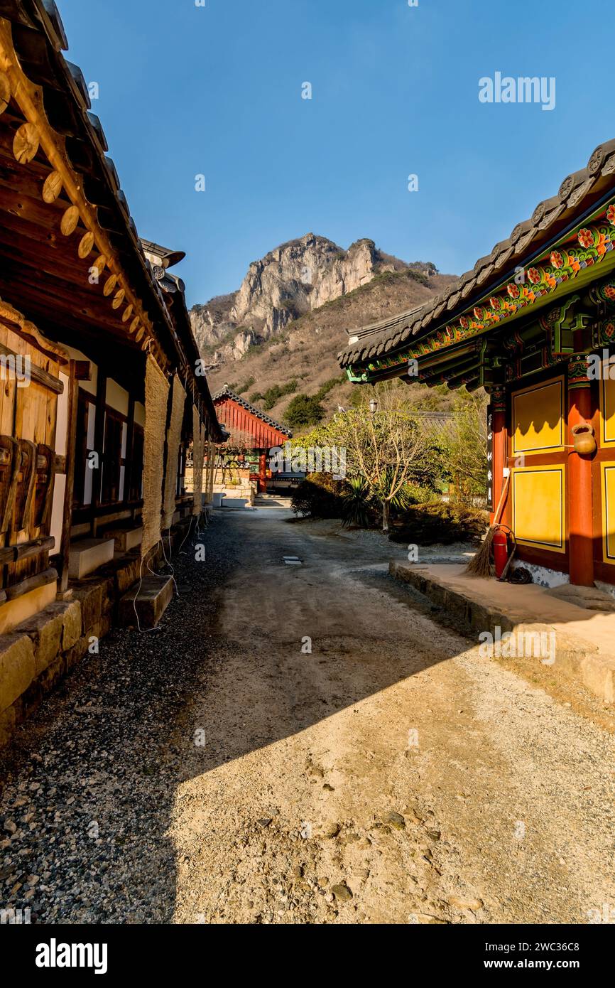Walkway between buildings at Buddhist temple with mountain cliffs in ...