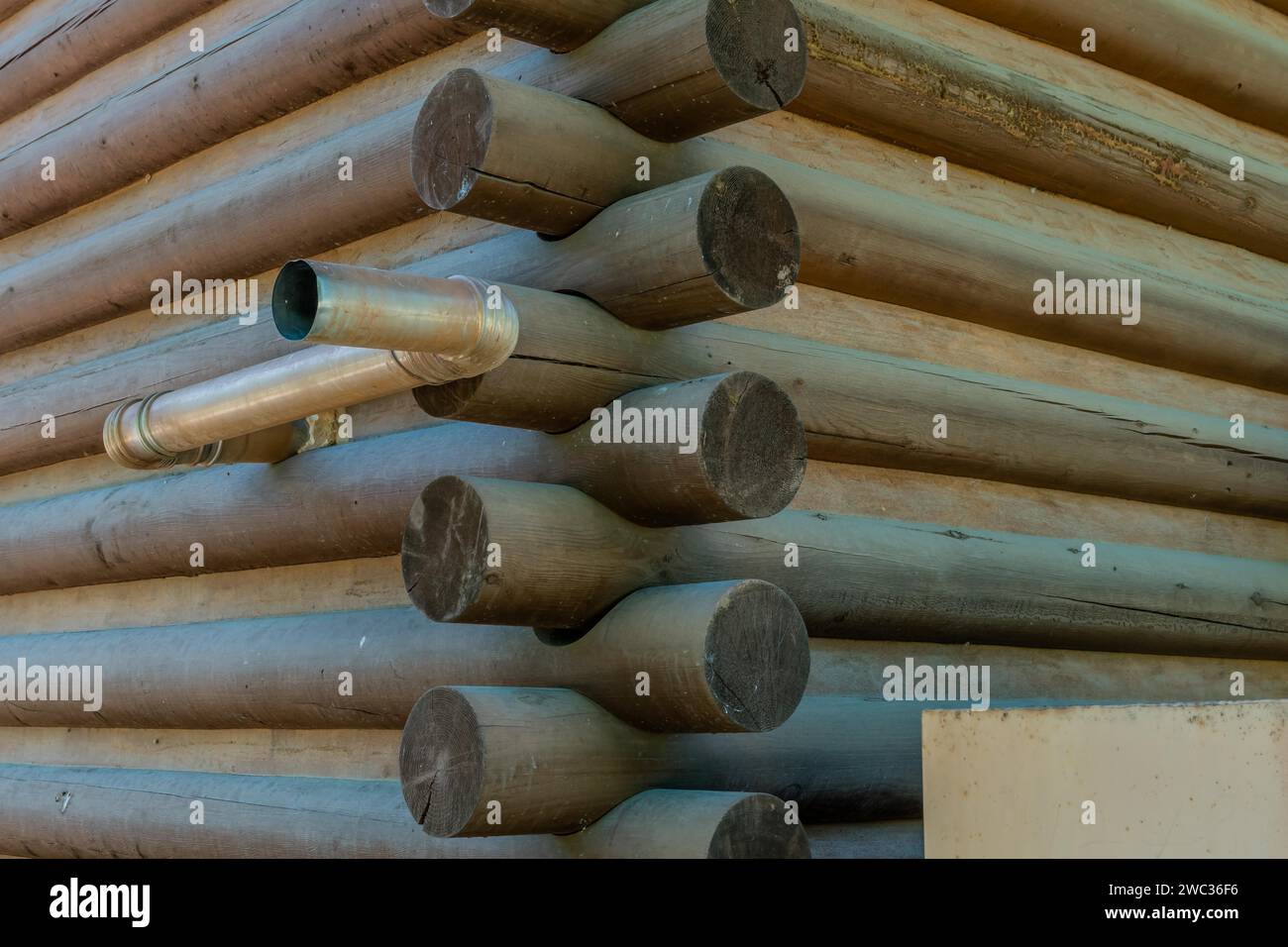 Metal exhaust pipe protruding from side exterior wall of wood log ...