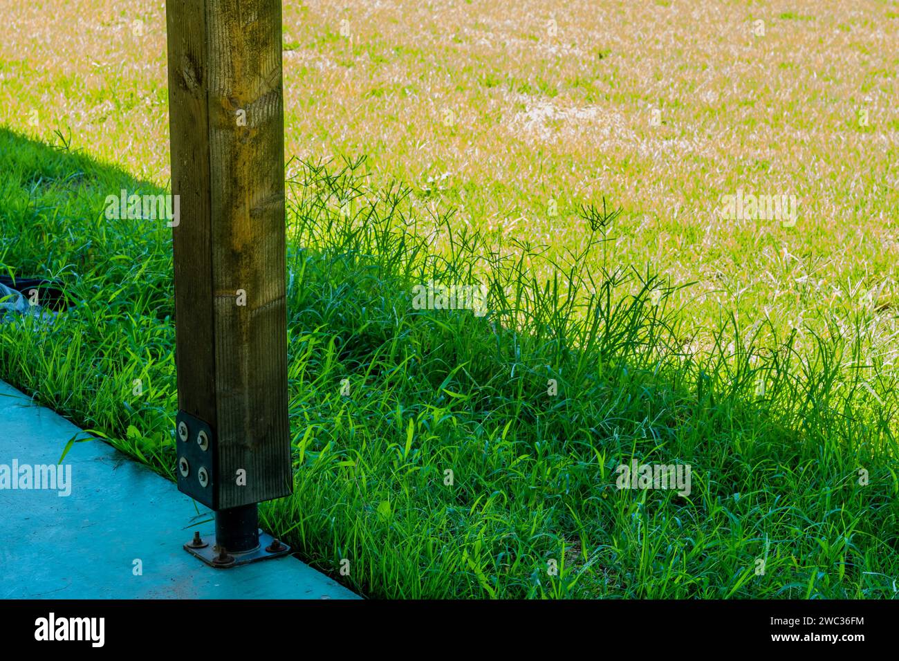 Square wooden support column attached to concrete base using metal ...