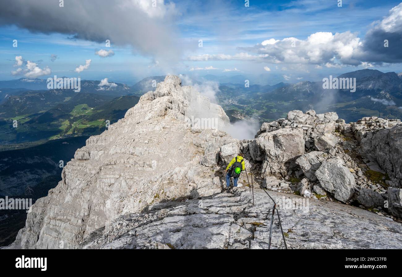 Climber on a via ferrata secured with steel rope, narrow rocky ridge ...