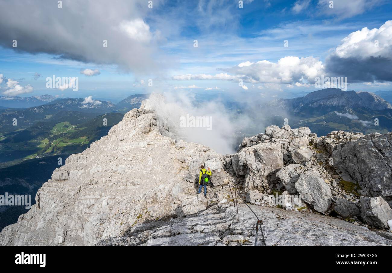 Climber on a via ferrata secured with steel rope, narrow rocky ridge ...
