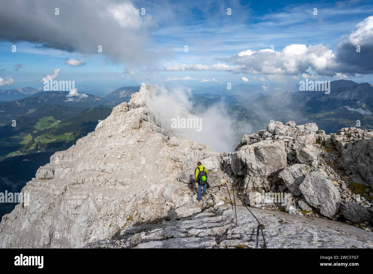 Climber on a via ferrata secured with steel rope, narrow rocky ridge ...