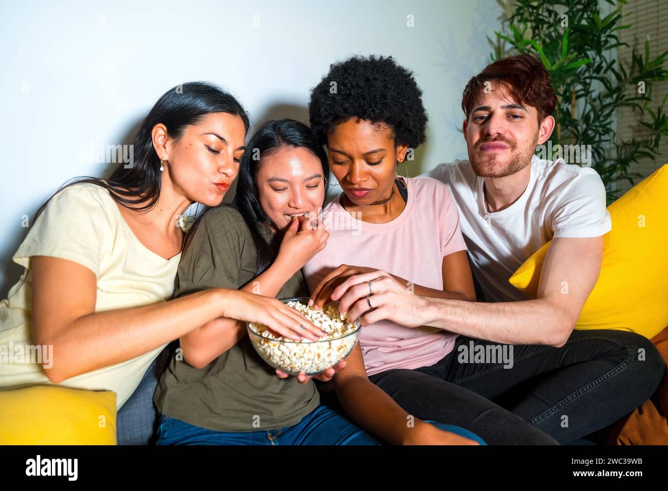 Friends enjoying popcorn during a movie night on the sofa at home Stock ...