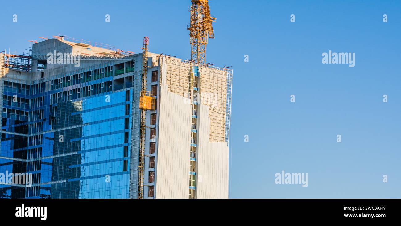Yellow crane elevator attached to side of building that is under ...