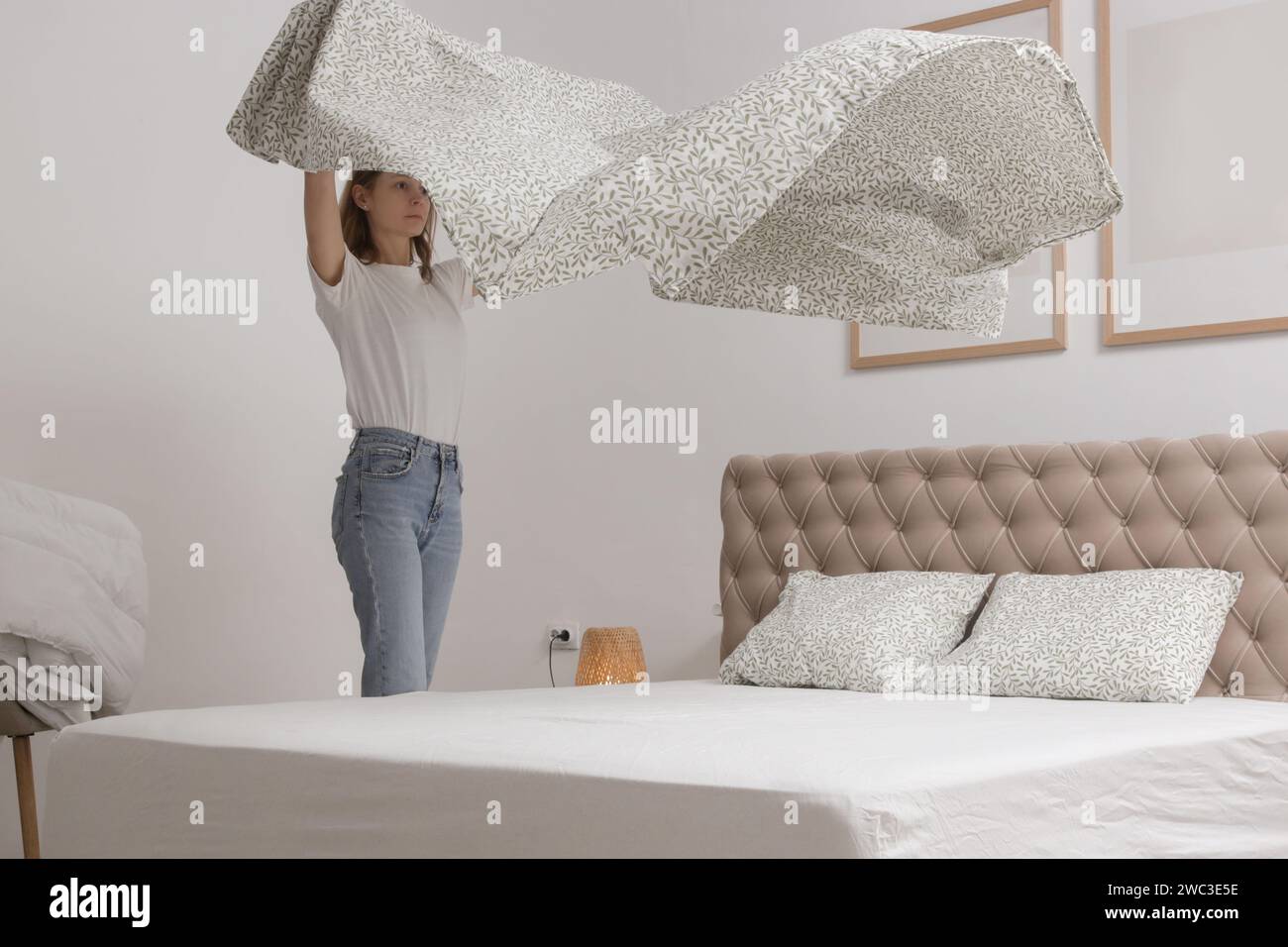 Woman changing bed linens at home in her bedroom, cozy domestic ...