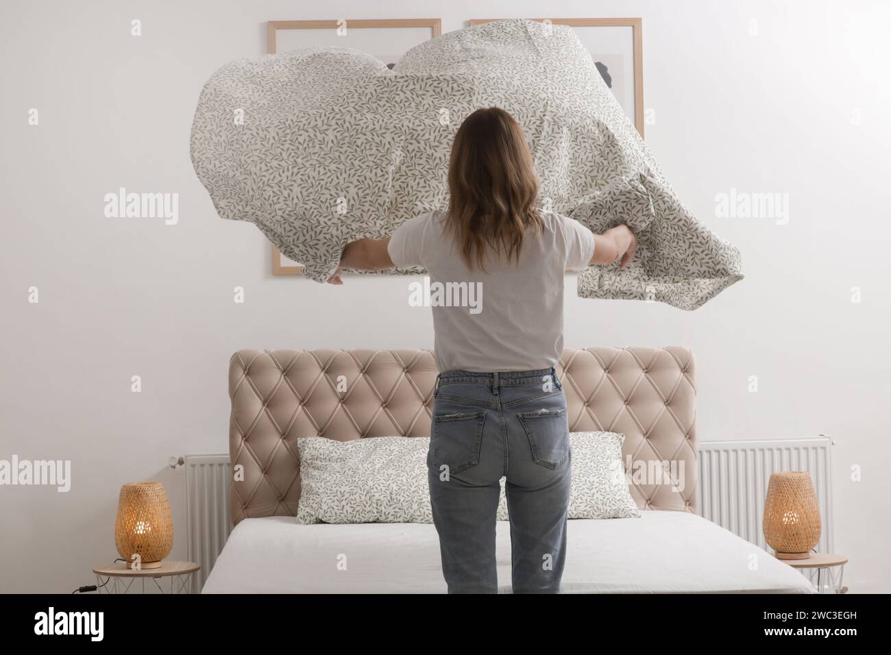 Woman changing bed linens at home in her bedroom, cozy domestic ...