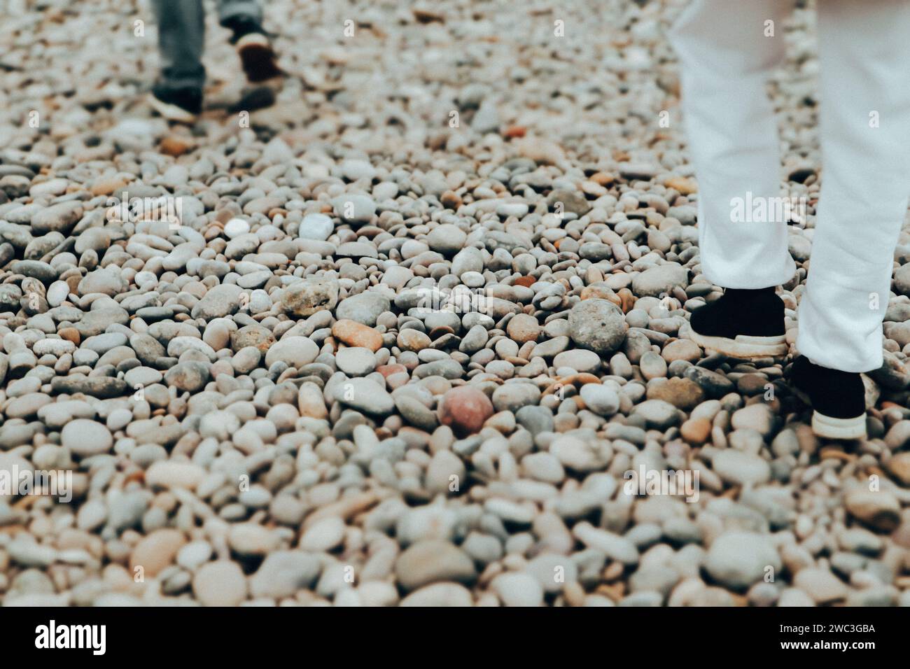 White gravel stones on a beach. People in white clothes in classy ...