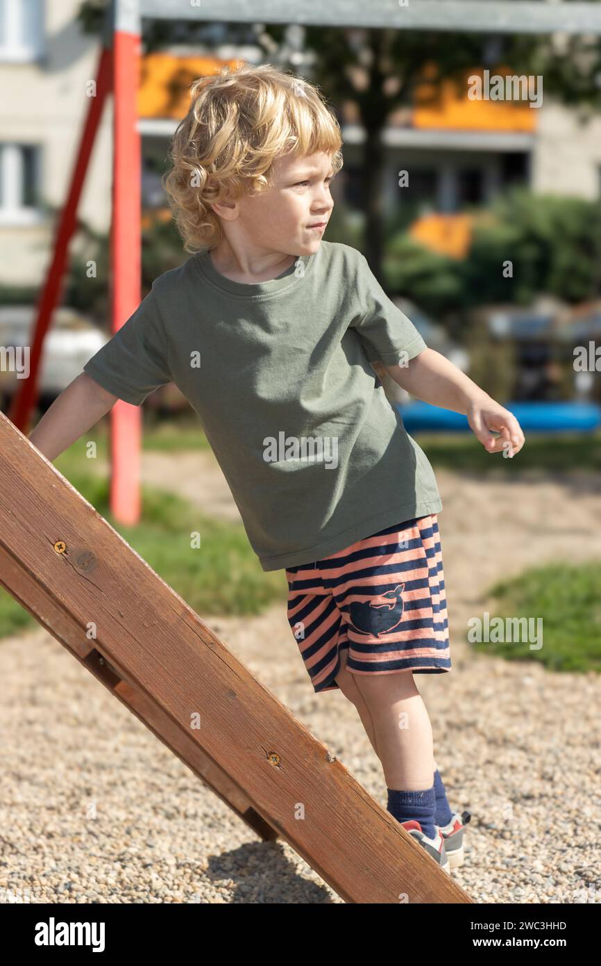 A little boy looks around on the steps of the slide Stock Photo - Alamy
