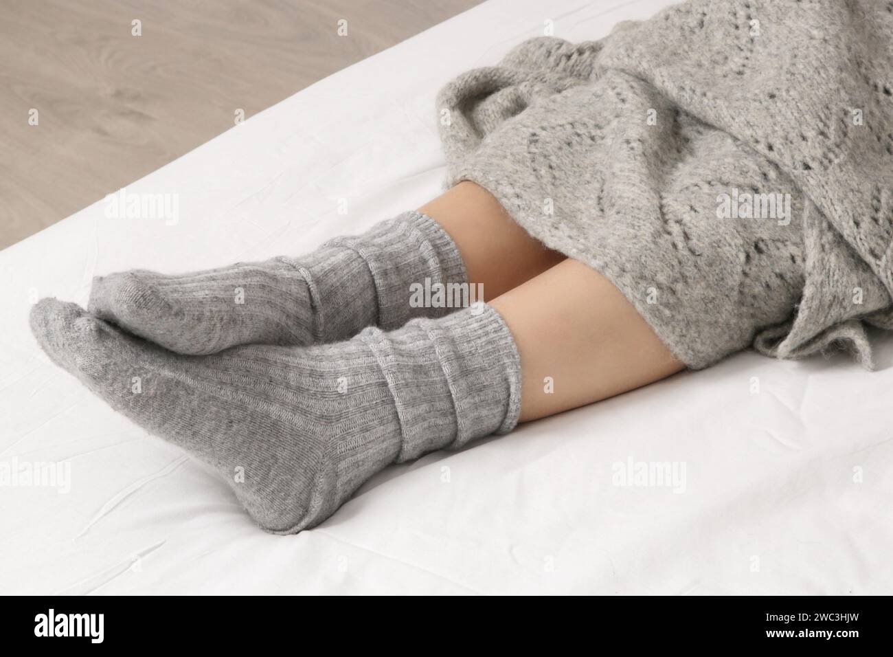 Pair of female legs wearing cozy grey cashmere socks under blanket in ...