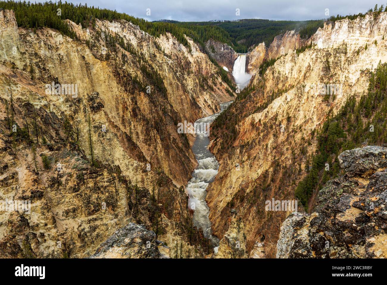 River and waterfall flow through the jagged yellow cliffs of Grand ...