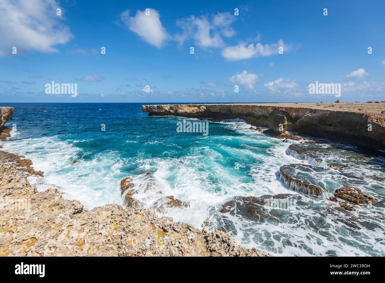 Waves and white foam form as waves crash in a rocky horseshoe bay with ...