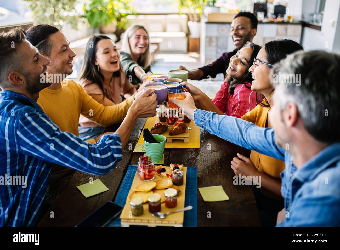 Smiling multiracial group of young people having breakfast together ...