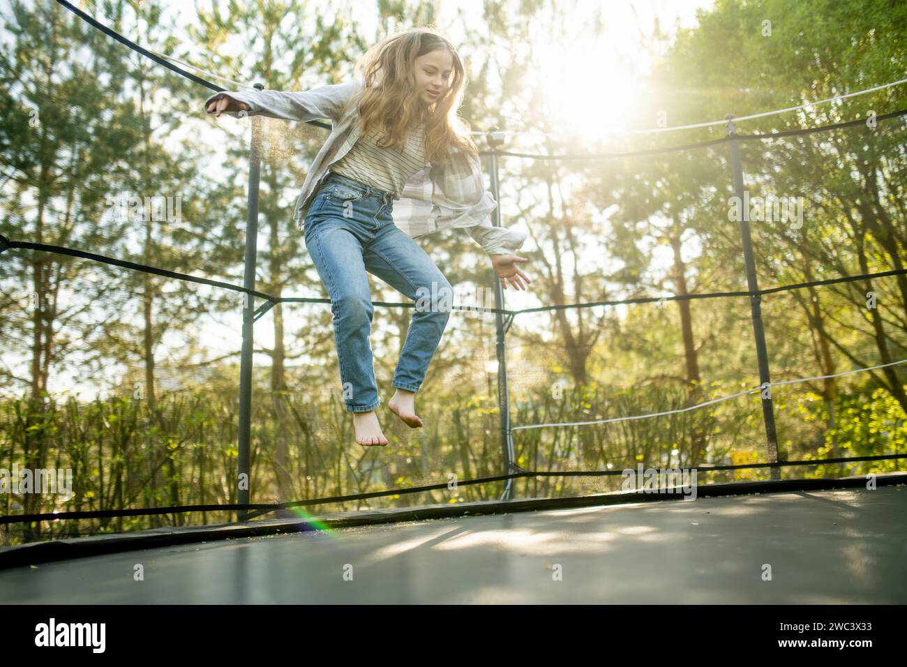 Teenage girl jumping on a trampoline in a backyard. Sports and ...
