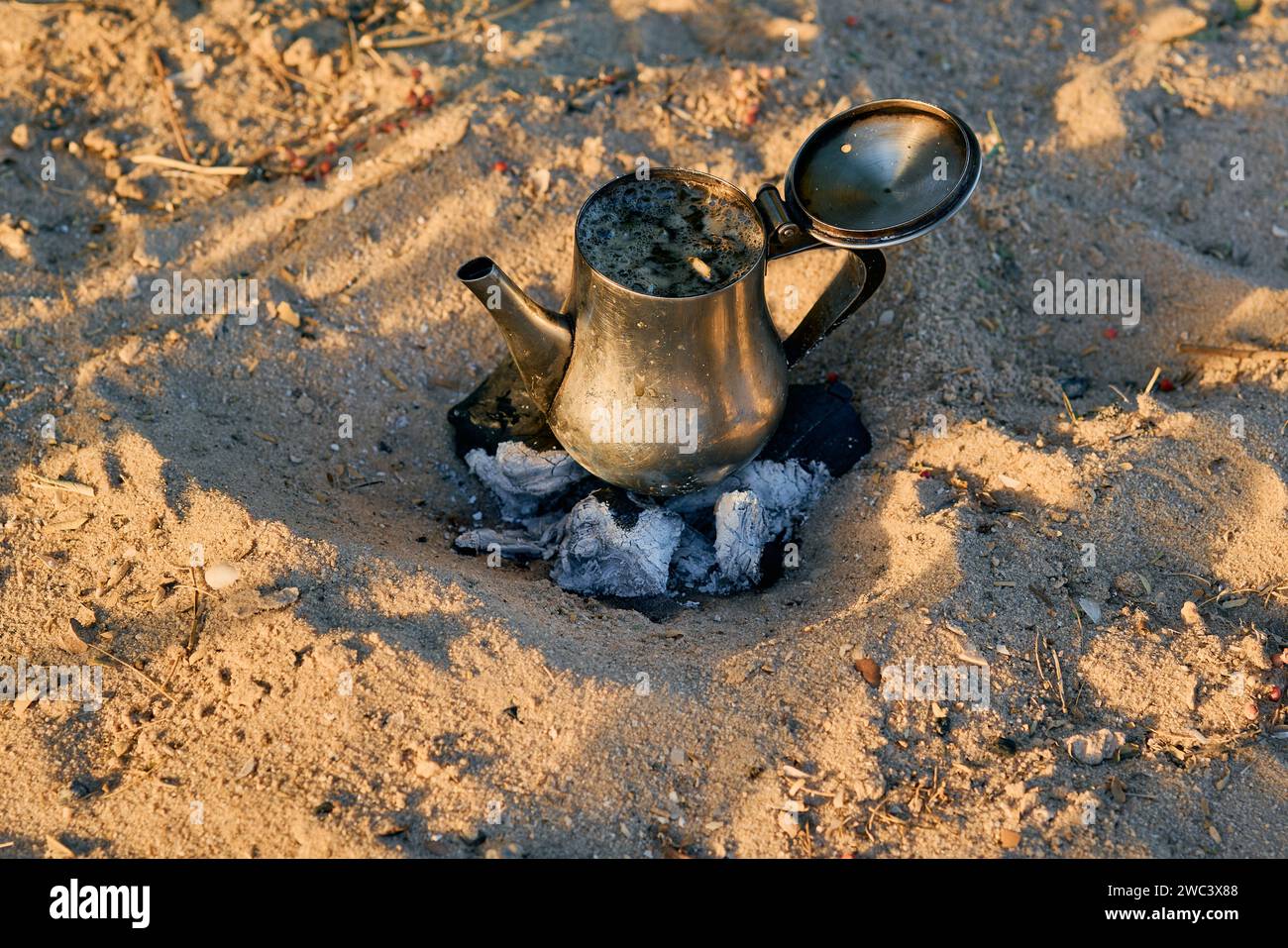 outdoor Moroccan tea in the making on sand and charcoal Stock Photo - Alamy