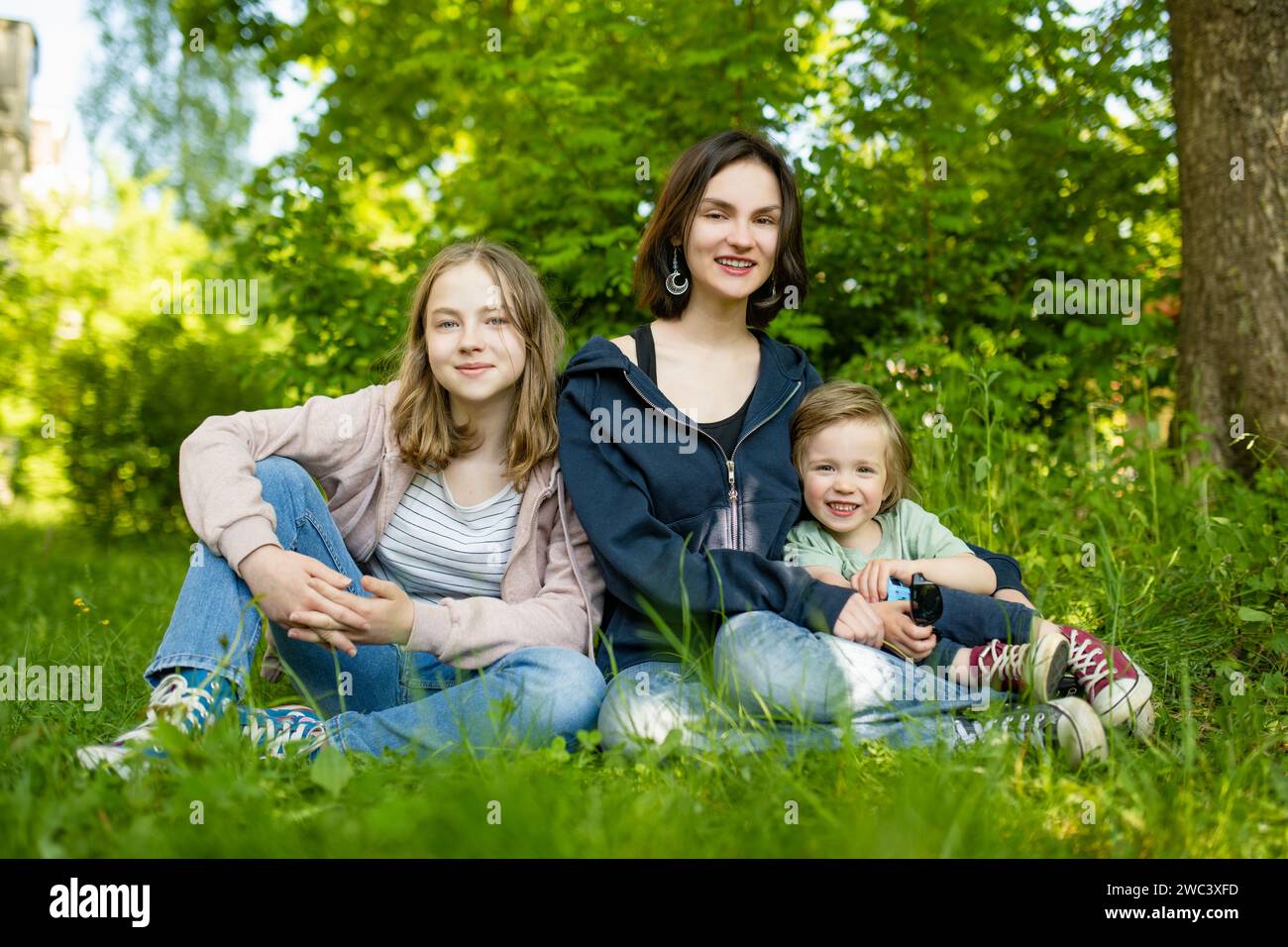 Cute big sisters cuddling with their toddler brother. Adorable teenage ...