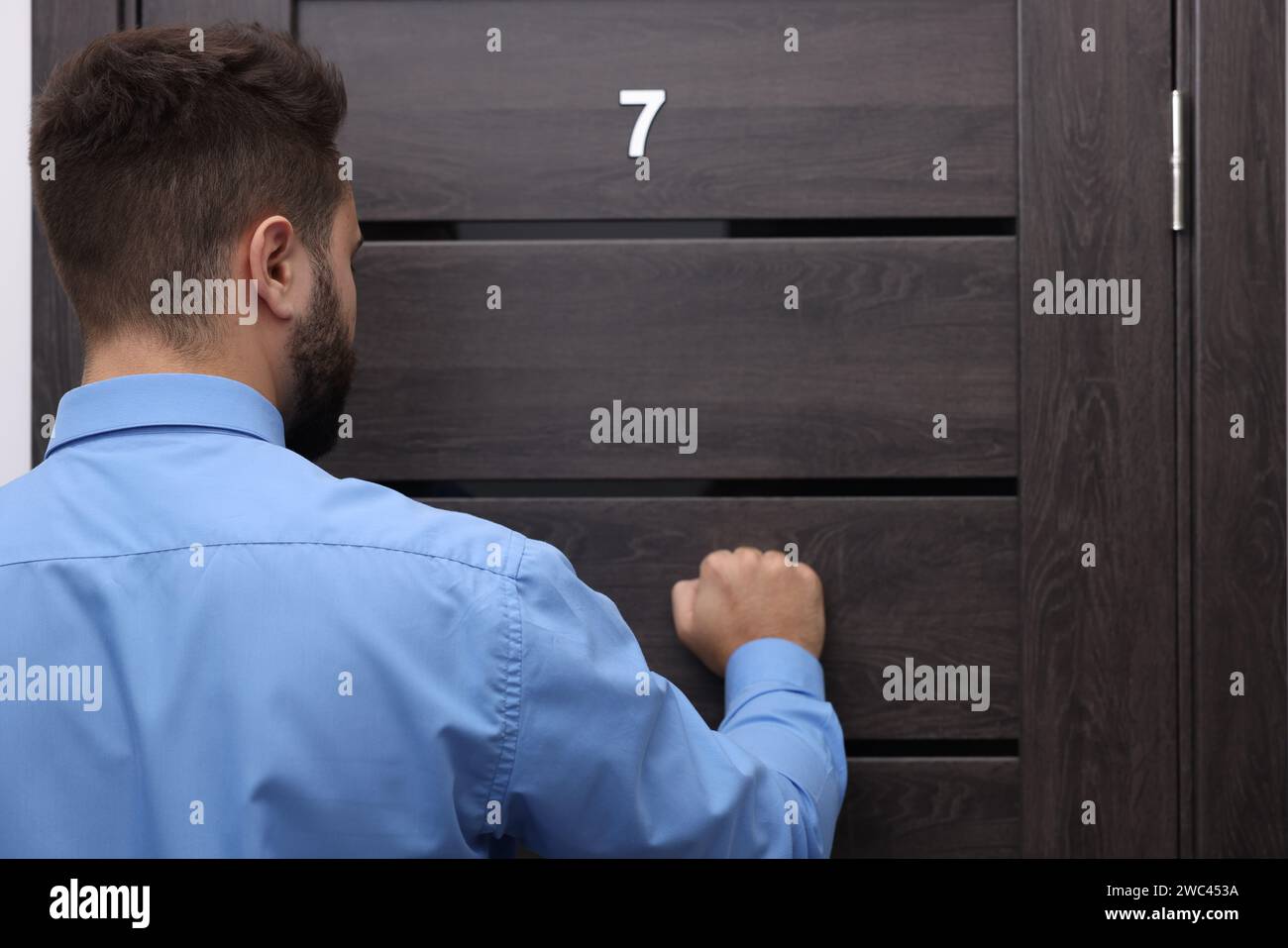 Collection agent knocking on wooden door, back view Stock Photo - Alamy