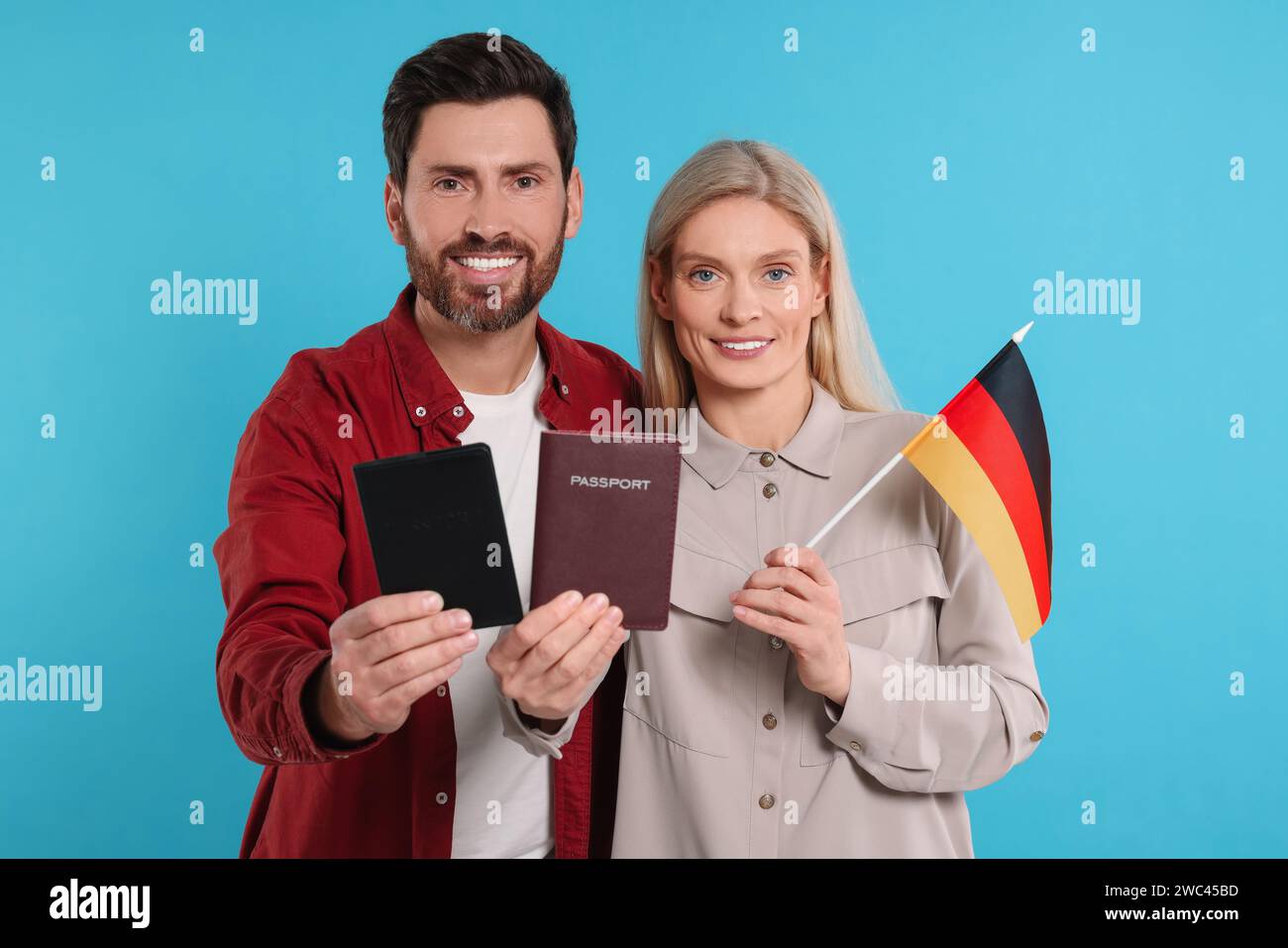 Immigration. Happy couple with passports and flag of Germany on light ...