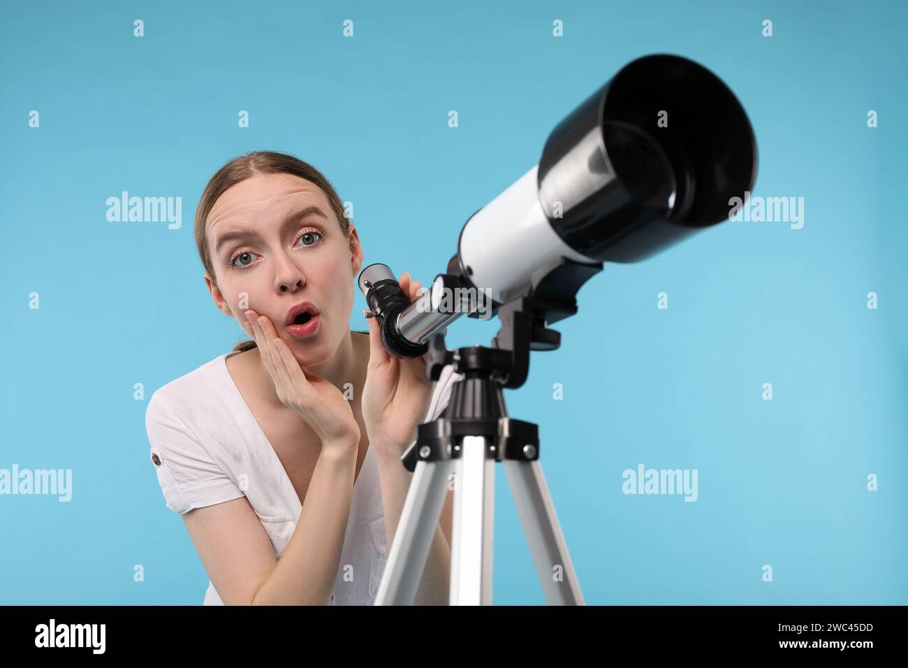 Surprised astronomer with telescope on light blue background Stock ...
