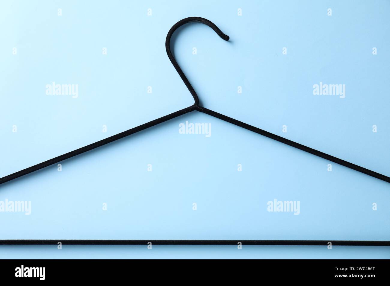 One black hanger on light blue background, top view Stock Photo - Alamy