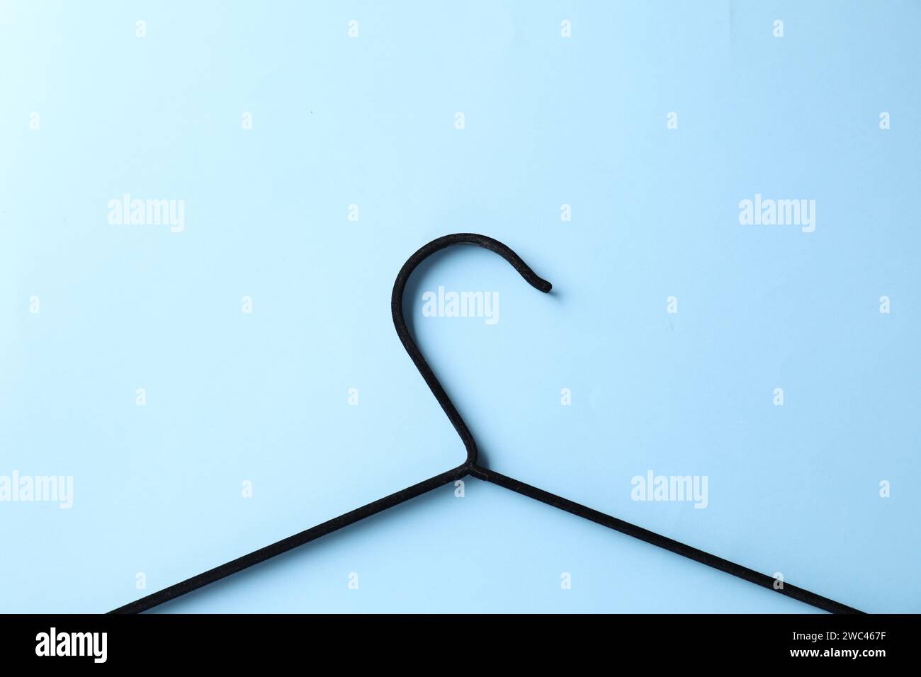 One black hanger on light blue background, top view. Space for text ...
