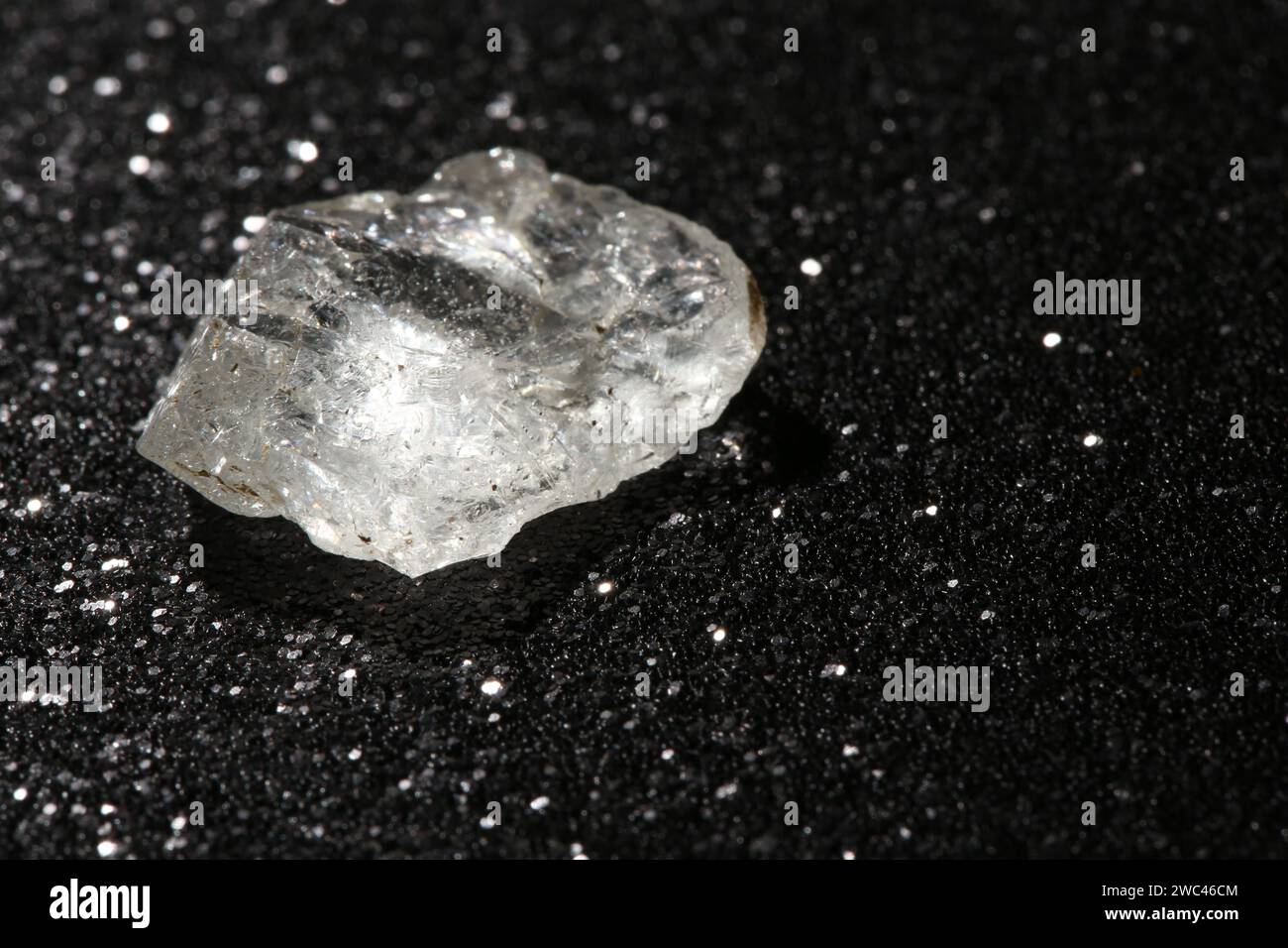 Beautiful rough diamond on dark shiny background, closeup. Space for ...