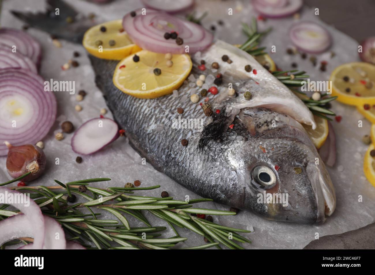 Fresh raw dorado fish with spices, lemon and onion on table, closeup ...