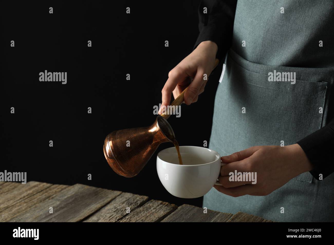 Turkish coffee. Woman pouring brewed beverage from cezve into cup at ...