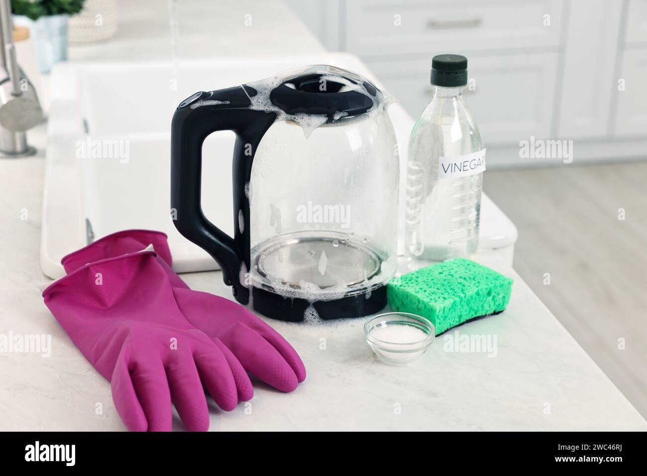 Cleaning electric kettle. Bottle of vinegar, sponge, rubber gloves and ...