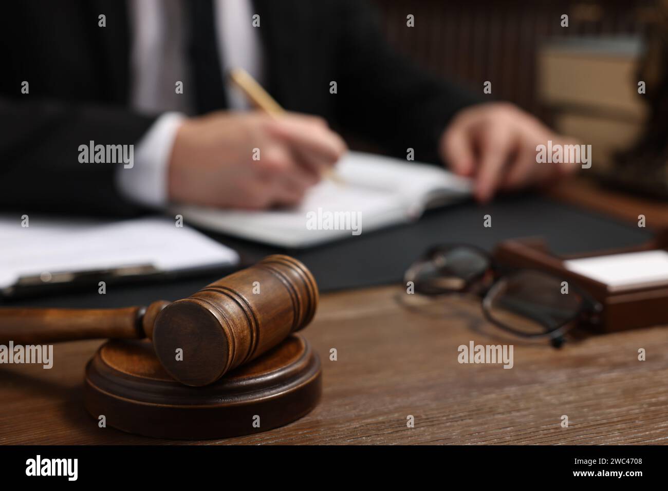 Lawyer taking notes at wooden table, focus on gavel Stock Photo - Alamy