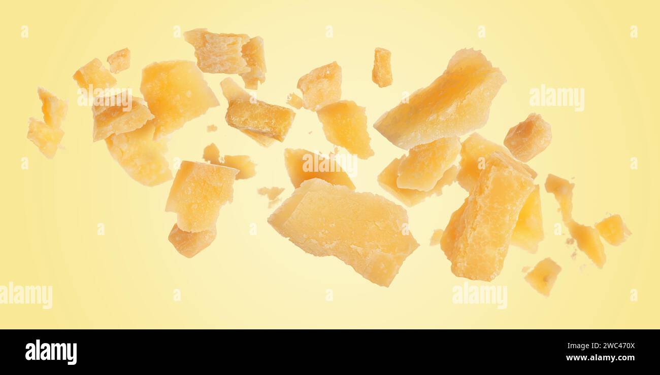 Tasty parmesan cheese falling on light golden background. Banner design ...