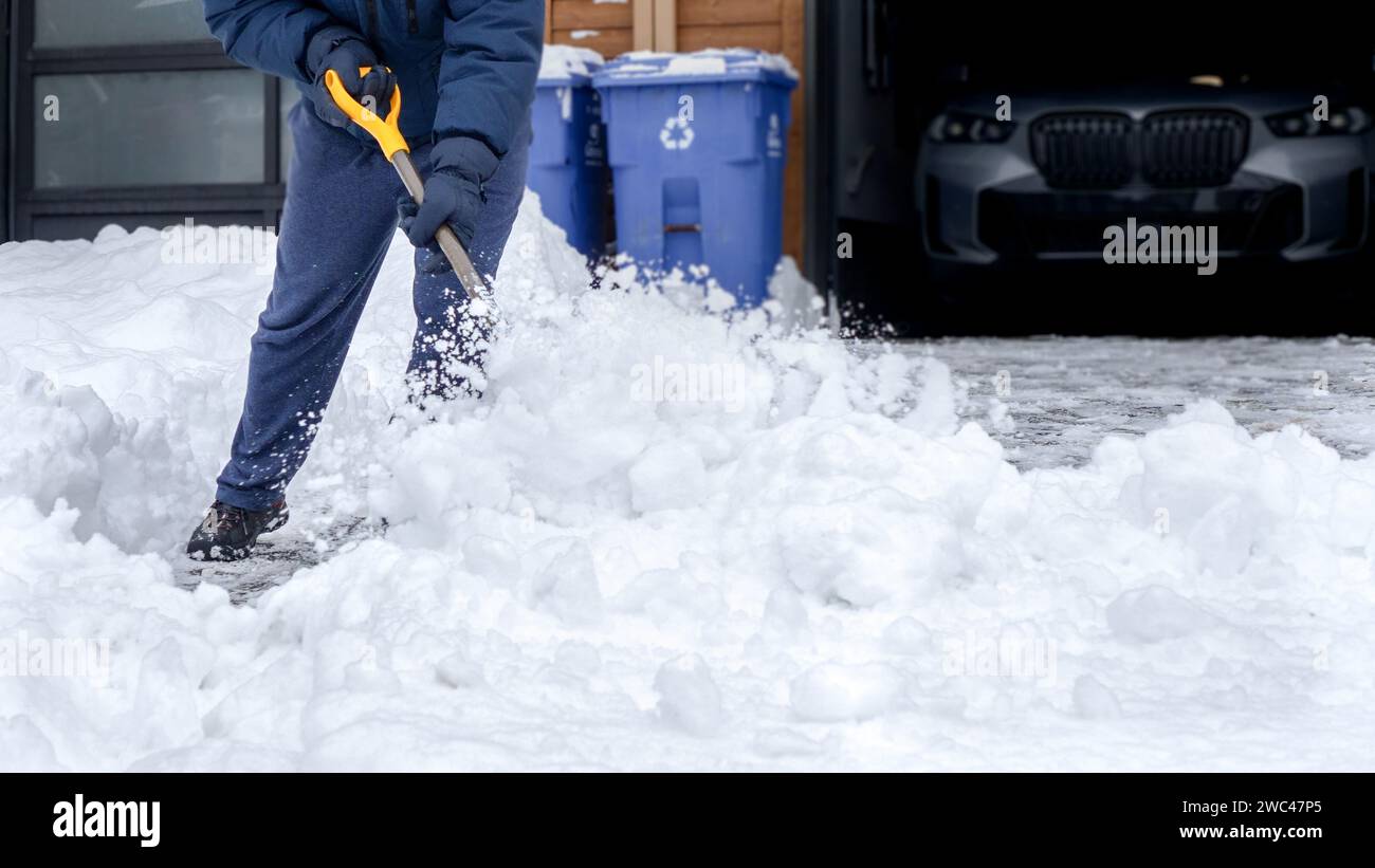 Man shoveling snow off of his driveway after a winter storm in Canada ...