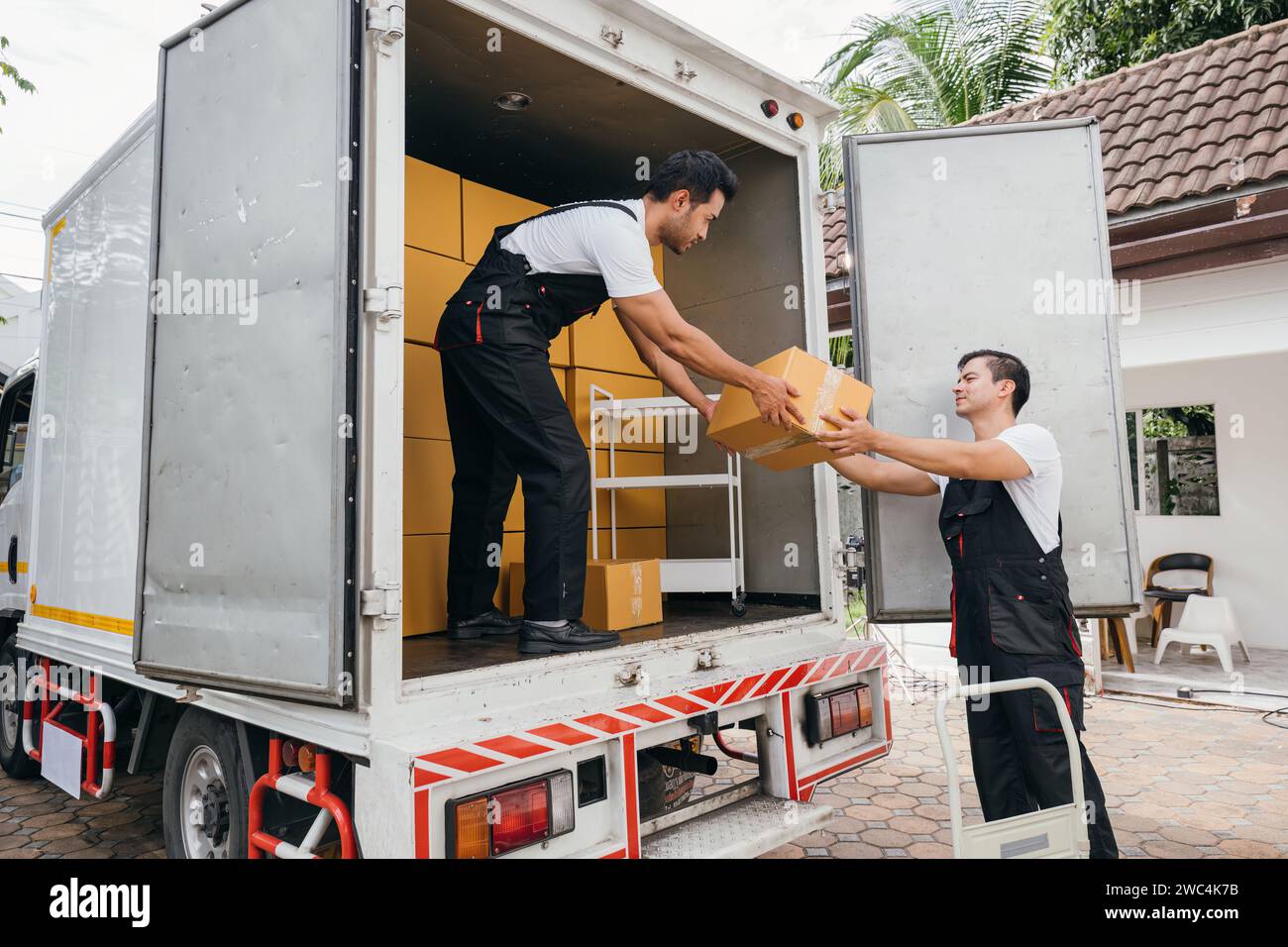 In uniform employees work together to unload boxes from the moving truck for customer relocation ...
