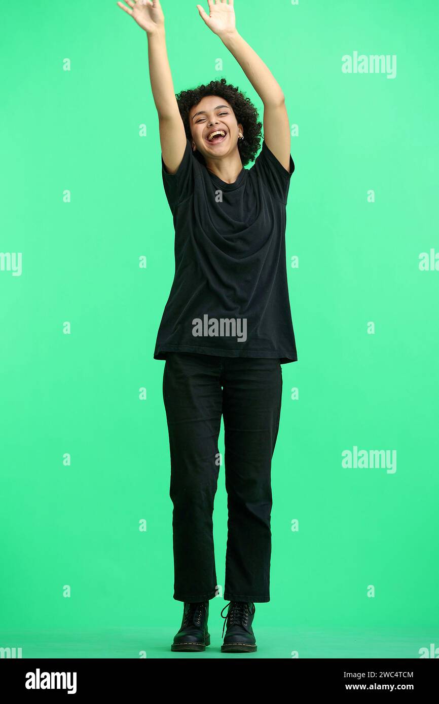 A woman, full-length, on a green background, waving her arms Stock ...