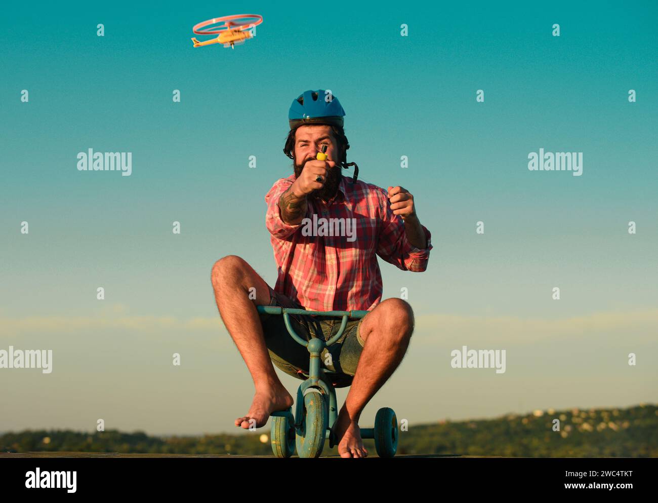 Childhood memory. Funny man riding a small bicycle Stock Photo - Alamy