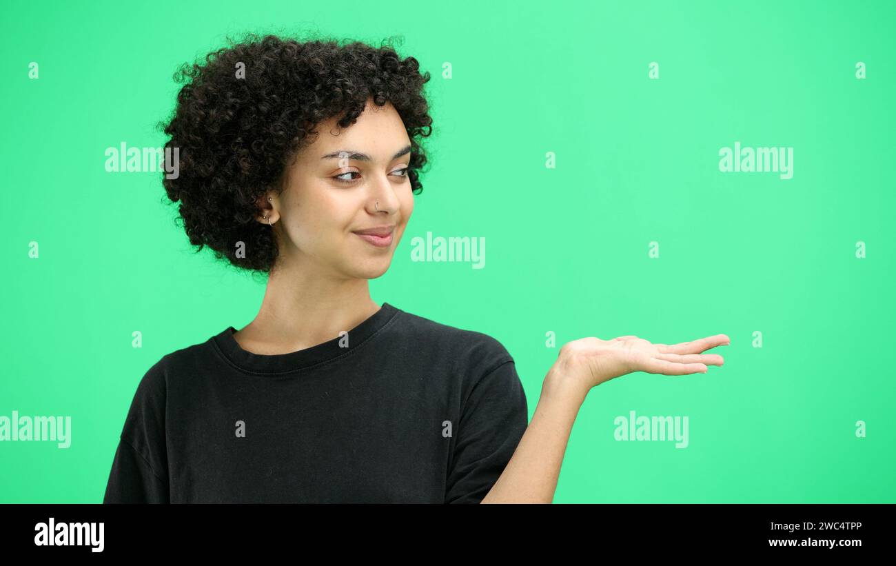 A woman, close-up, on a green background, points to the side Stock ...