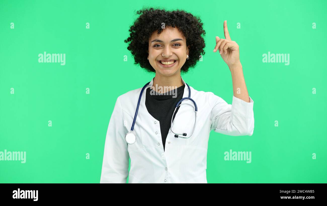 Female doctor, close-up, on a green background, pointing up Stock Photo ...