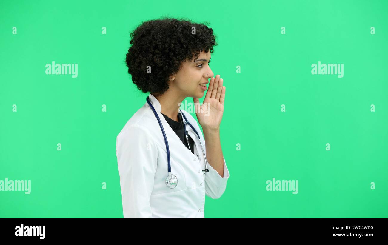 Female doctor, close-up, on a green background, tells a secret Stock ...