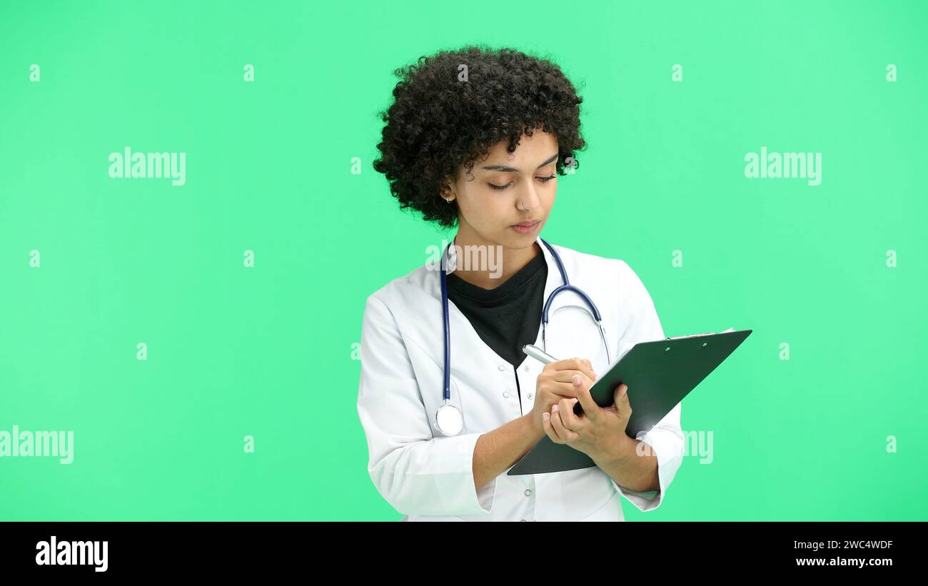 Female doctor, close-up, on a green background, writes Stock Photo - Alamy