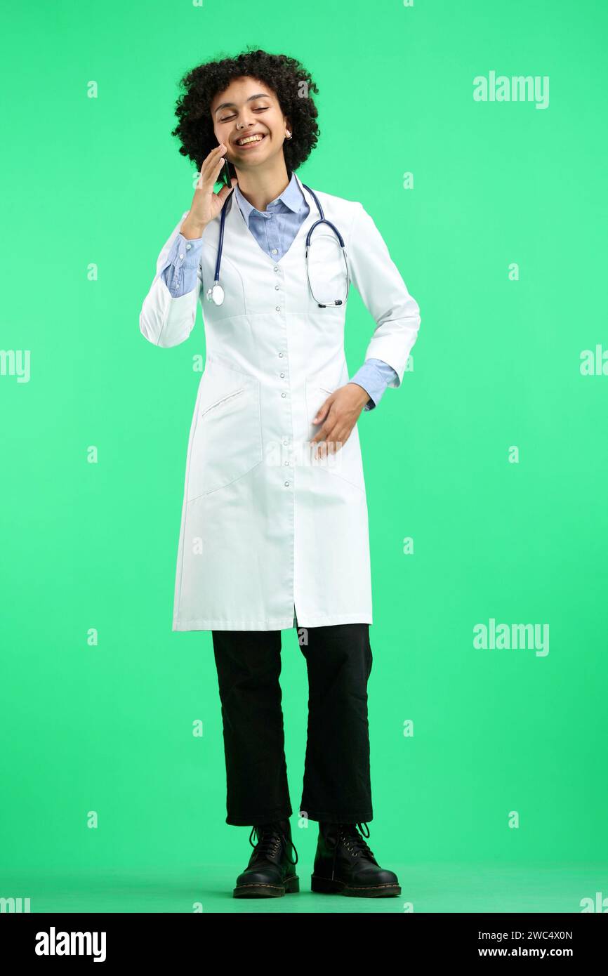 Female doctor, full-length, on a green background, with a phone Stock ...