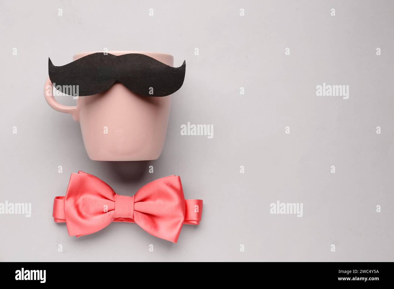 Composition with cup, paper mustache and bow tie on grey background ...