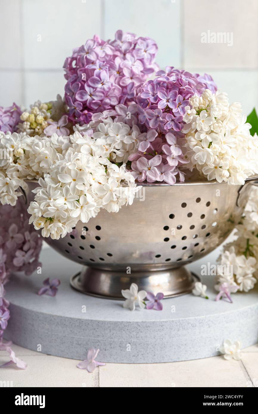 Colander with Beautiful fragrant lilac flowers near white tile Stock ...