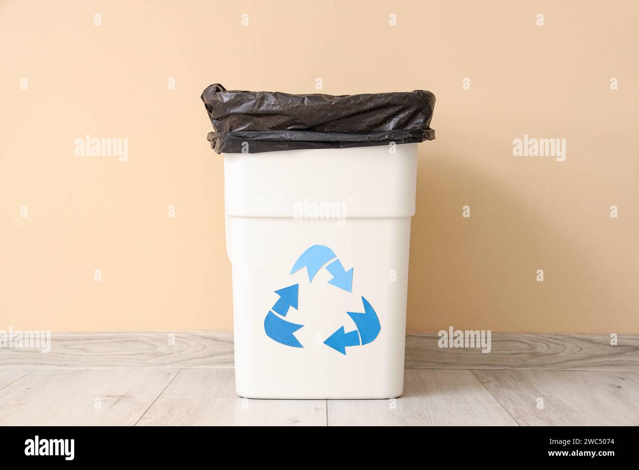 Empty trash bin with garbage bag and recycle logo near beige wall Stock ...