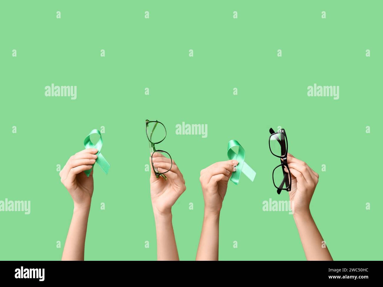 Female hands with ribbons and eyeglasses on green background. Glaucoma ...