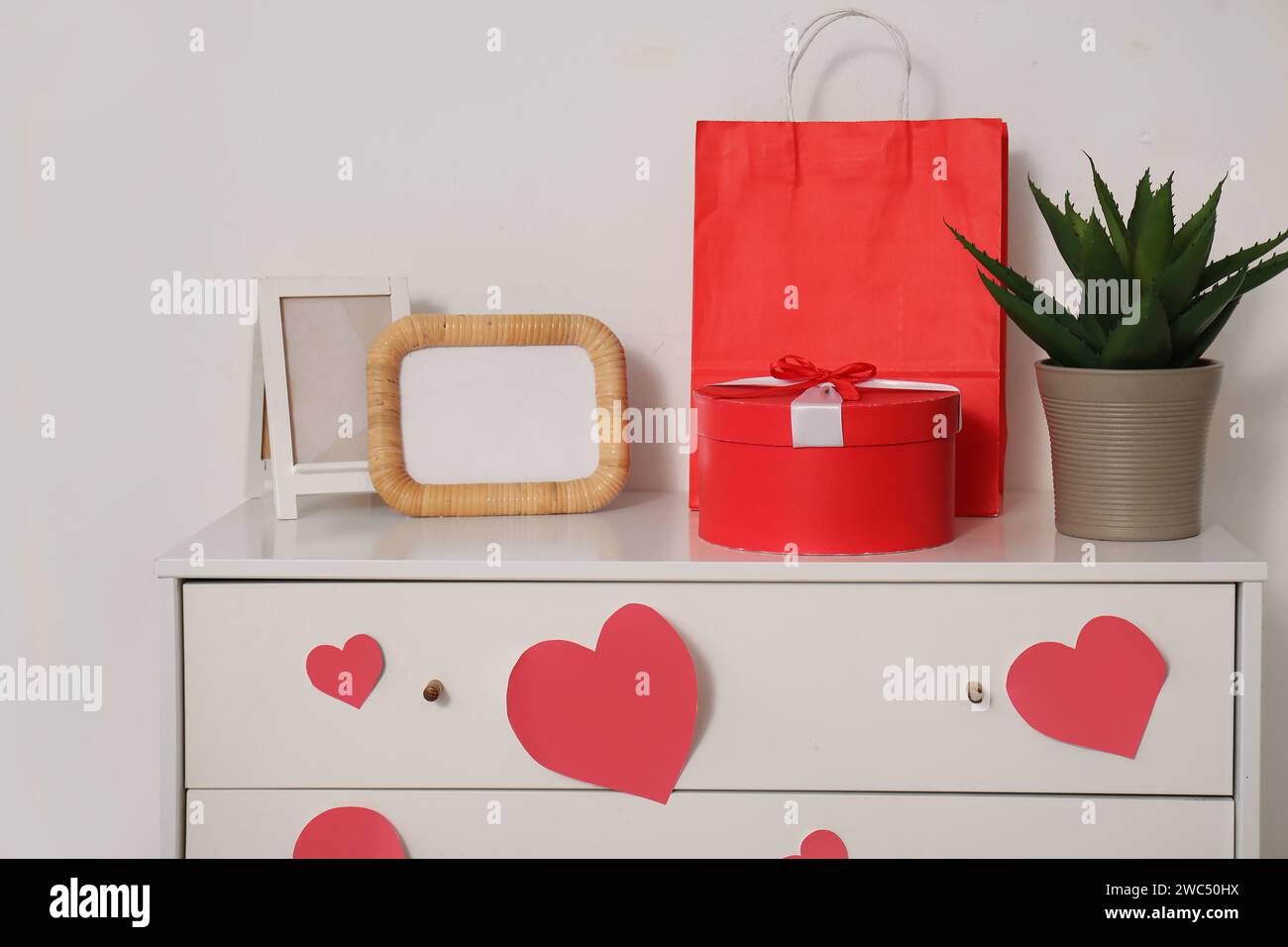 Chest of drawers with gift box, blank frame and paper hearts. Valentine ...
