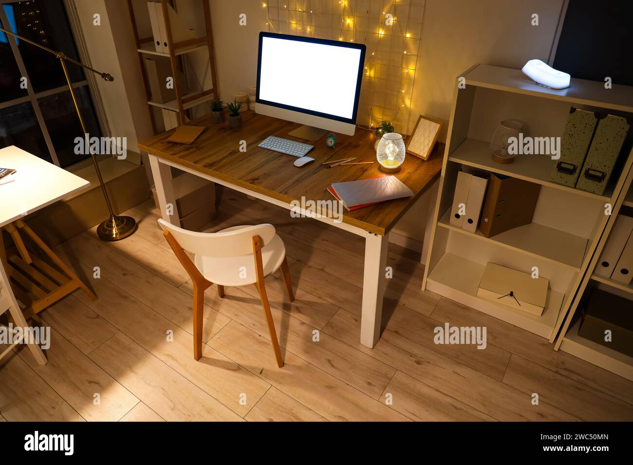Interior of office with workplace, shelf units and glowing lights at ...